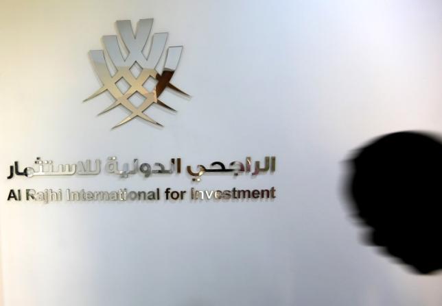 A man walks past the logo of Al Rajhi International for Investment at ...